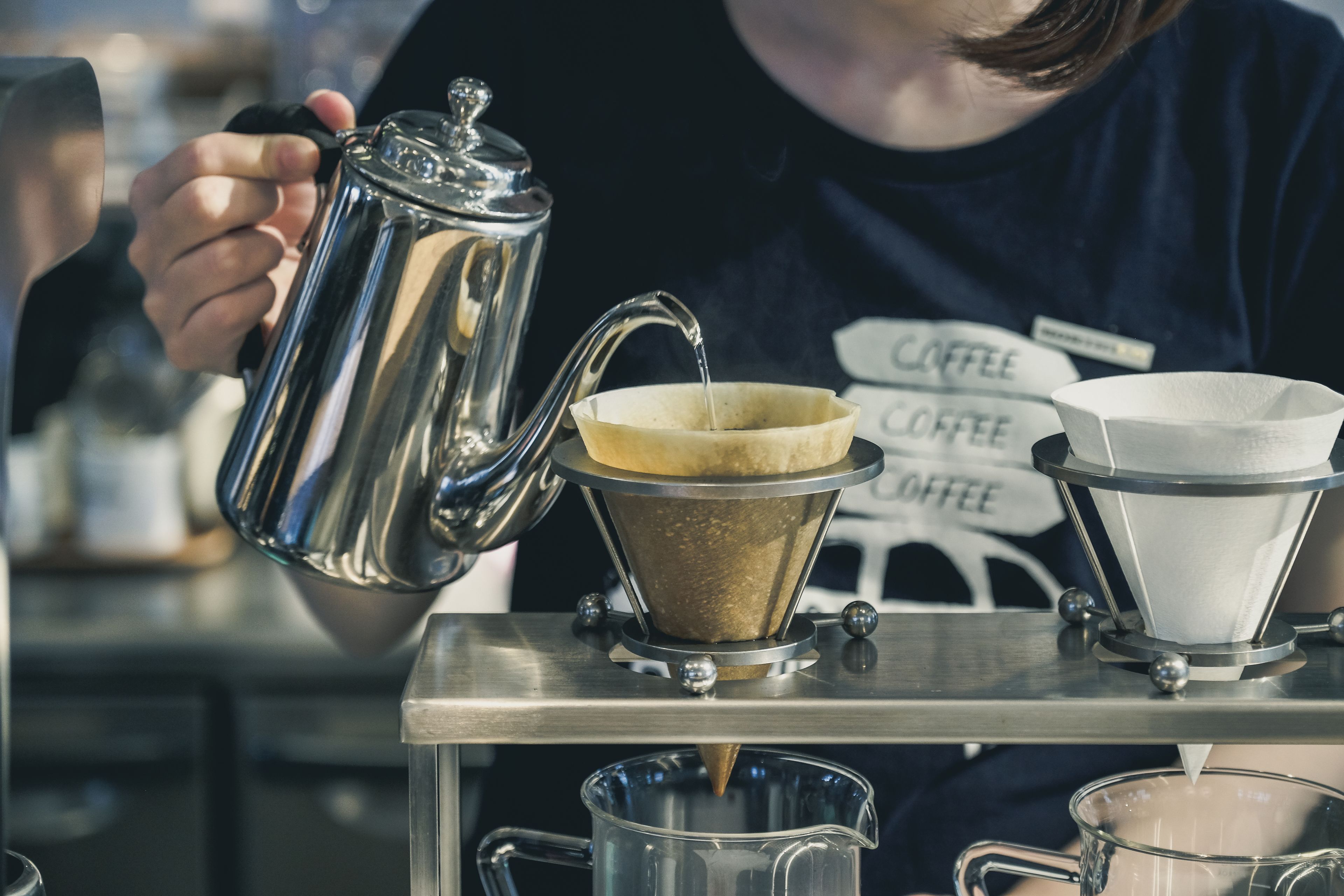 Uma estação para preparar café com chaleira de metal, filtro de café e cafeteira de gotejamento.