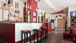 Uma área de bar com banquetas, prateleiras cheias de garrafas e uma tela de televisão.