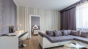 Uma sala de estar moderna com um sofá, uma mesa de centro de vidro e uma escrivaninha com abajur.