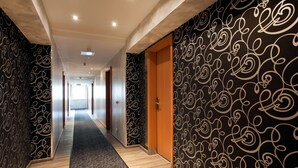 Um corredor com paredes estampadas, piso de madeira e uma área com carpete.