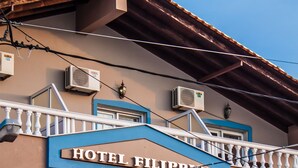 Um hotel chamado "HOTEL FILIPPO" com varanda, aparelhos de ar condicionado e um céu azul límpido.
