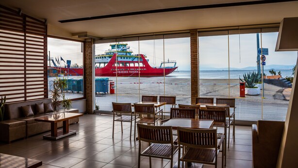 Um restaurante com vista para um ferry vermelho na água.