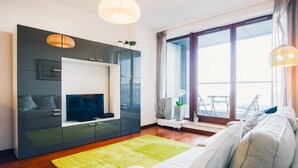 Uma sala de estar moderna com televisão de tela plana, sofá cinza e tapete verde.