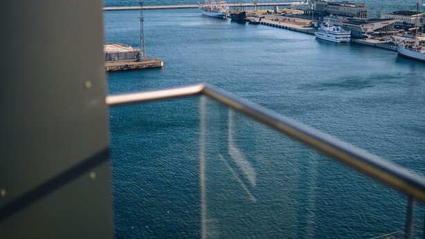 Vista de uma varanda com vista para uma marina, com barcos e céu claro.