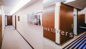 Um corredor com uma placa indicando "sea towers" e uma porta no fim.