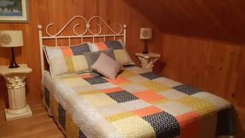 Quarto com cama, duas mesinhas de cabeceira e parede de madeira.