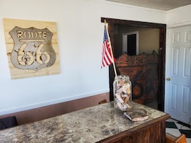 Uma placa de madeira com 'ROUTE 66' e uma bandeira americana, um pote com aparas de madeira e uma porta com a palavra 'BRASS'.