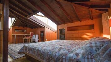 Quarto de sótão aconchegante com cama, escrivaninha e cadeira.