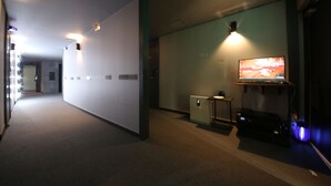 Um corredor com televisão de tela plana na parede, uma mesinha e um aquecedor no chão.