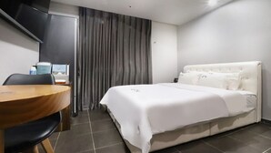 Quarto de hotel com cama, escrivaninha e cadeira.