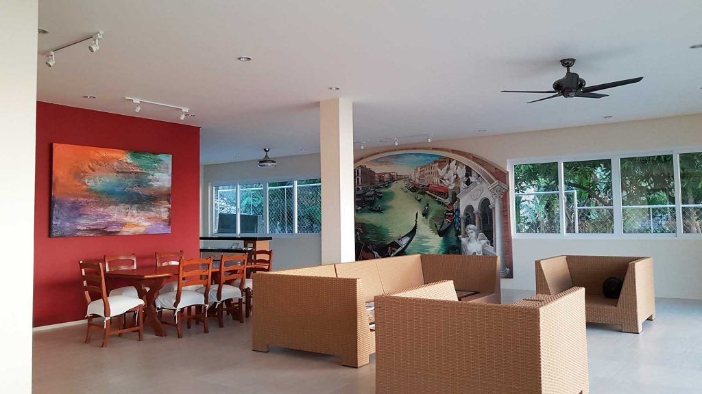 Um quarto espaçoso com área de jantar, móveis de vime e um mural com vista para a cidade.