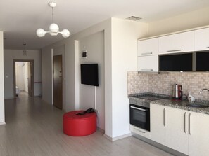 Uma cozinha moderna com armários brancos, forno embutido e bancada de granito.