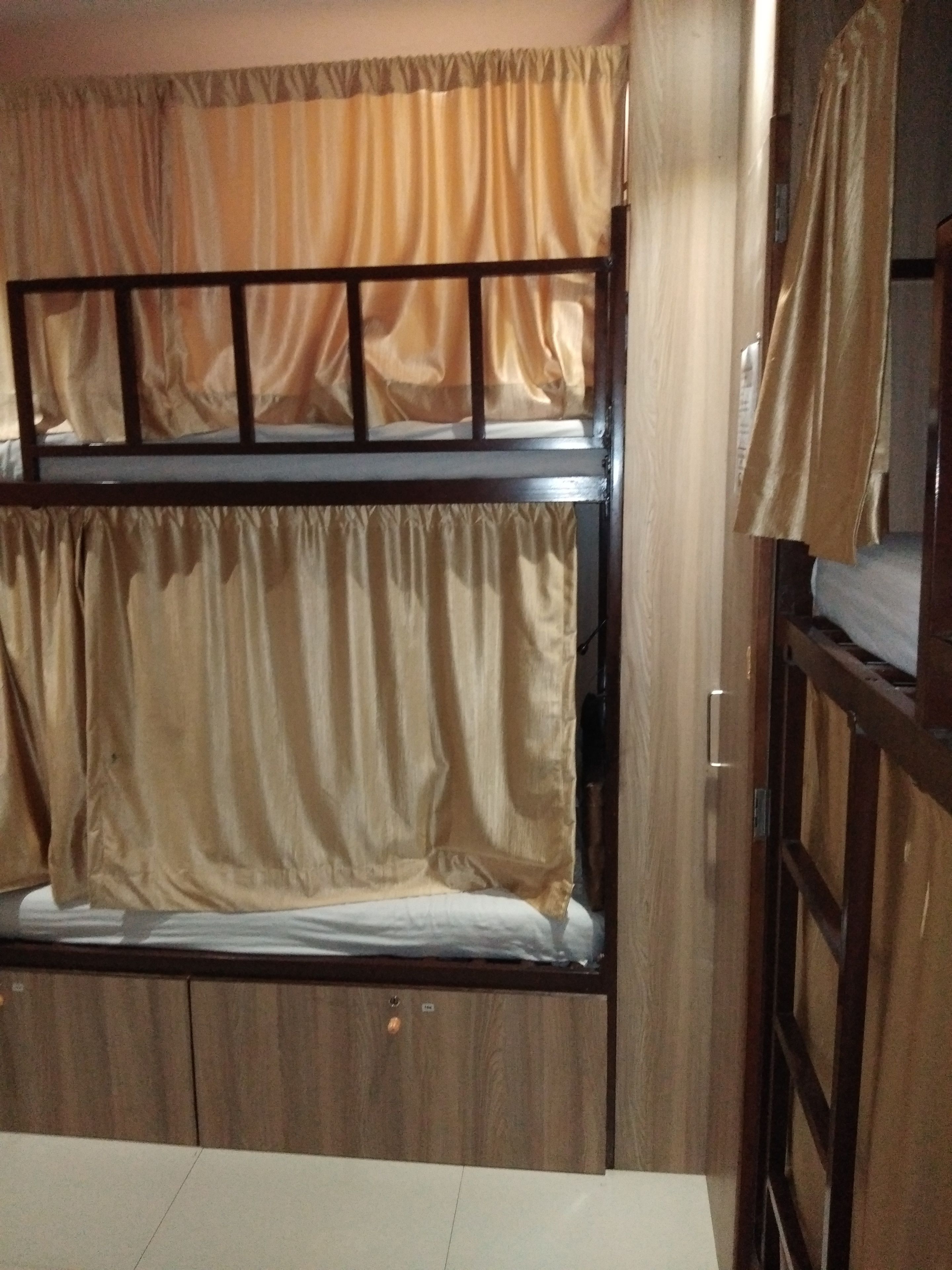 Uma cama beliche com cortinas, painéis de madeira e uma escada de metal.