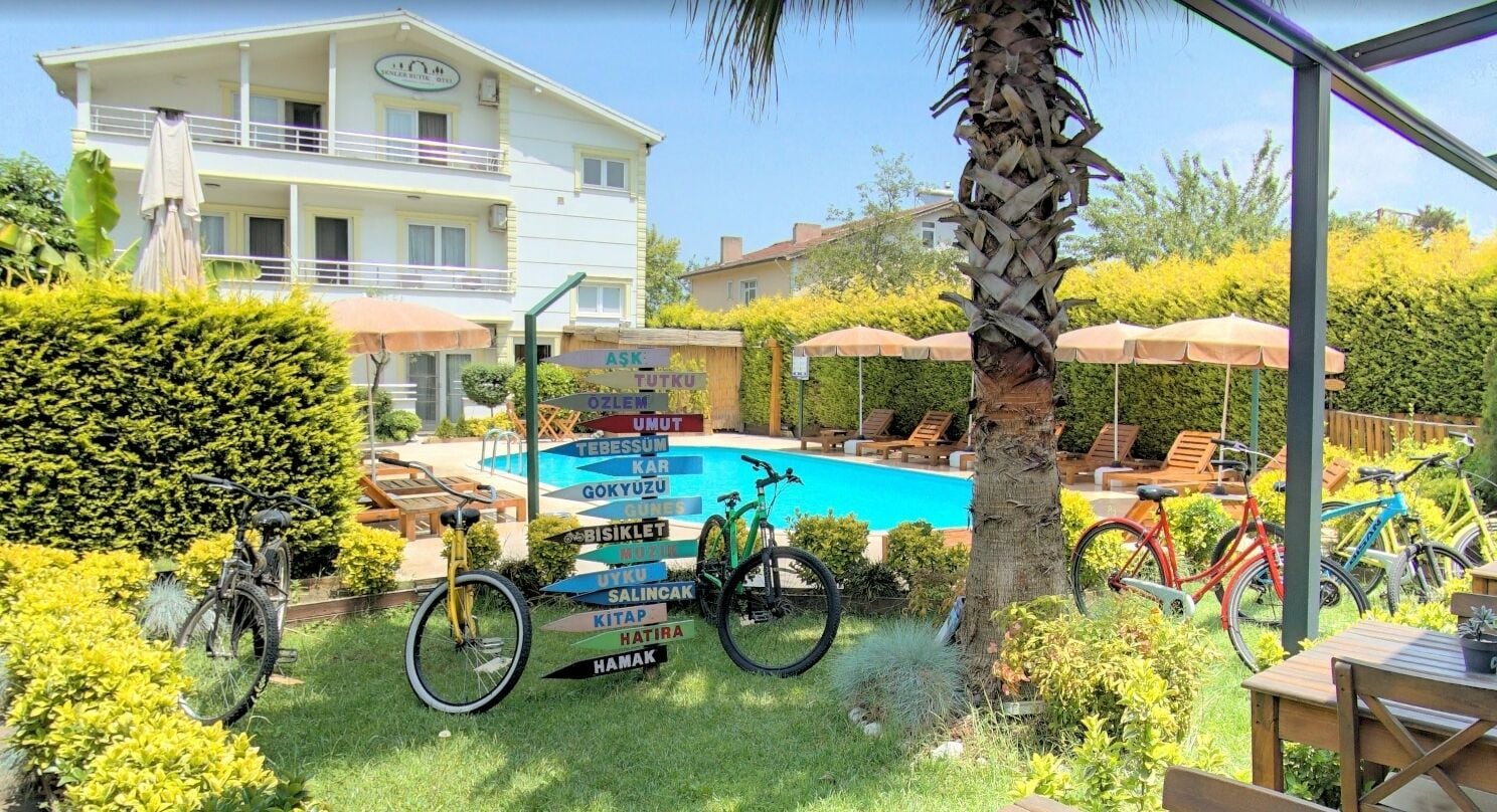 Uma área de piscina com bicicletas, um sinalizador de direções e um edifício com varandas.