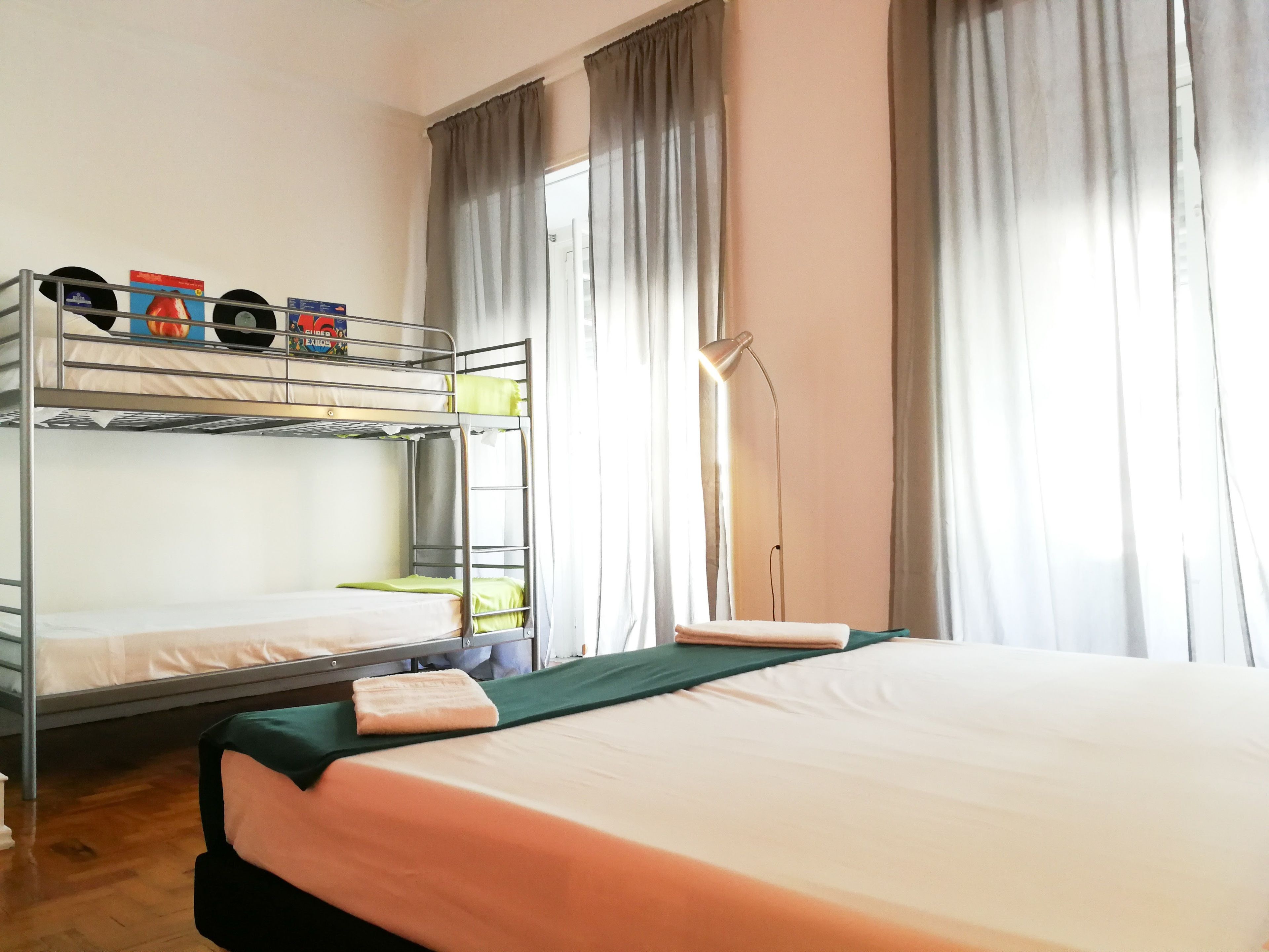 Quarto com beliche, uma escrivaninha, uma luminária e uma janela com cortinas.