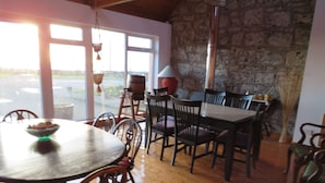 Uma sala de jantar com uma mesa redonda, cadeiras e uma parede de pedra.