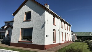 Um edifício de dois andares com fachada branca e detalhes em castanho, apresentando uma janela grande e uma pequena varanda.