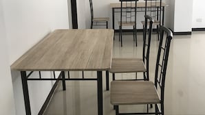 Uma sala de jantar com uma mesa de madeira comprida e várias cadeiras. Há uma pintura na parede acima da mesa.