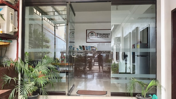 Entrada com porta de vidro para uma Pousada Turística, com interior visível incluindo balcão e área de estar.
