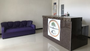 Uma área de recepção com um sofá roxo e um balcão de atendimento exibindo um logotipo e nome.