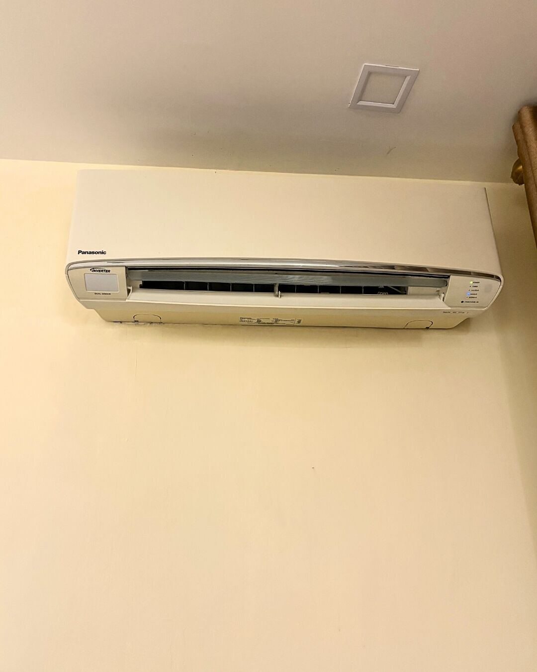 Ar-condicionado Panasonic fixado em uma parede bege.