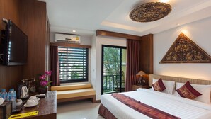 Quarto de hotel com cama, secretária com telefone, televisão e janela com persianas.