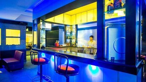Uma área de bar com banquetas, balcão e um bartender.