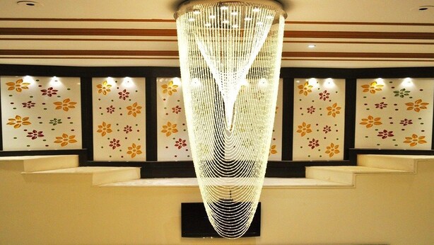 Uma área de recepção com um lustre moderno, obras de arte florais emolduradas e uma paleta de cores neutras.
