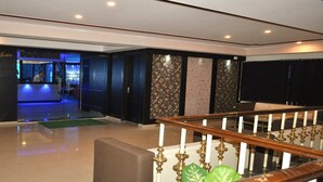 Um lobby de hotel moderno com área de bar, escadaria e balcão de recepção.