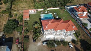 Vista aérea de um bairro residencial com uma casa grande, piscina, várias varandas e um gramado bem cuidado.