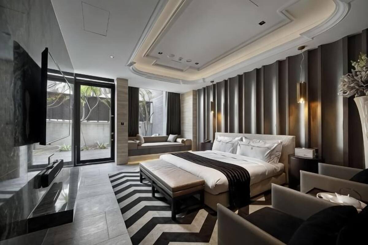 Quarto moderno com cama grande, área de estar, televisão e banheiro com banheira.