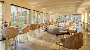Uma sala de jantar espaçosa com tetos altos, grandes janelas e móveis modernos.