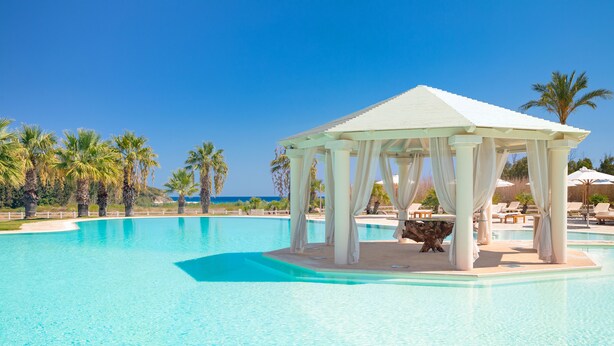 Uma piscina azul límpida com um gazebo e espreguiçadeiras.
