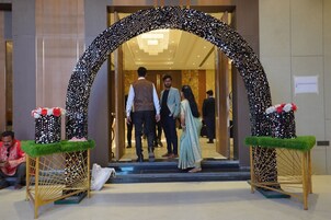 Uma entrada imponente com um arco decorativo e duas pequenas mesas com garrafas.