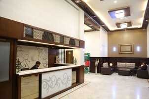 Uma área de recepção com balcão, assentos e um painel decorativo.