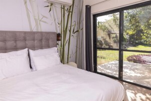 Quarto com uma cama grande, janela e vista para um jardim.