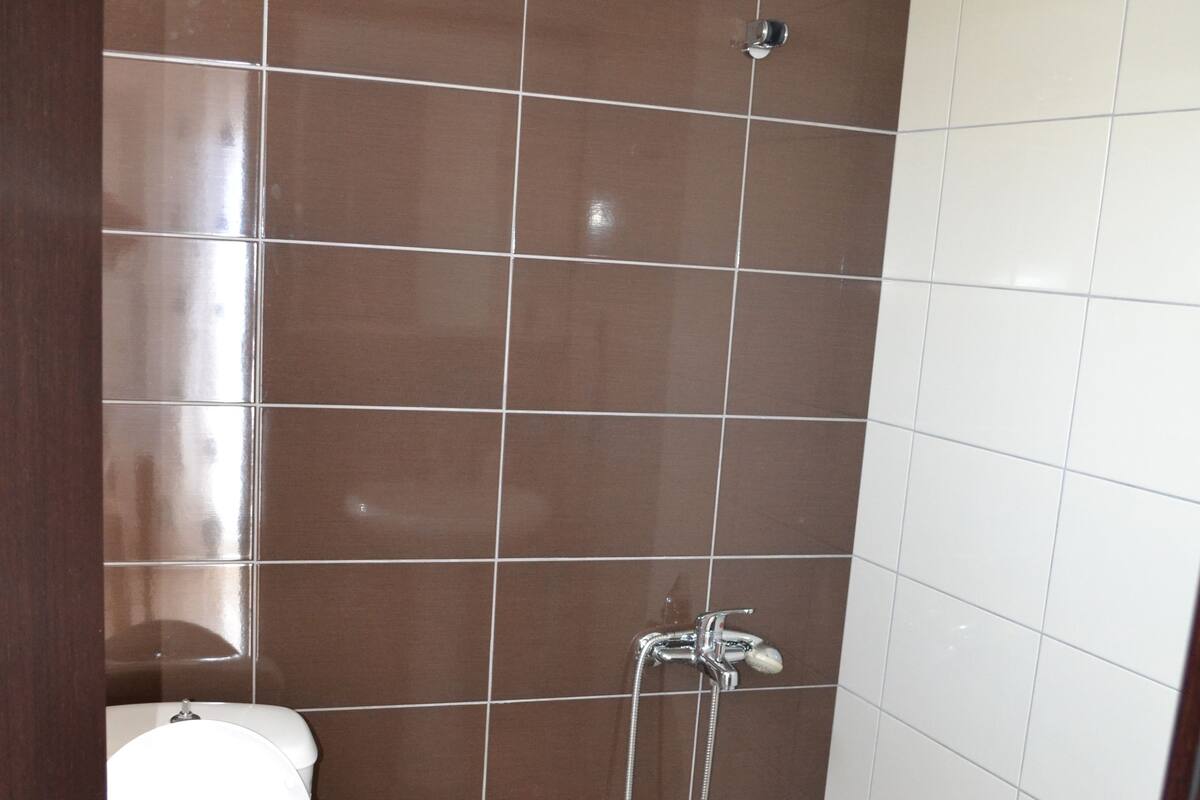 Um espaço pequeno e fechado com chuveiro, vaso sanitário e pia.