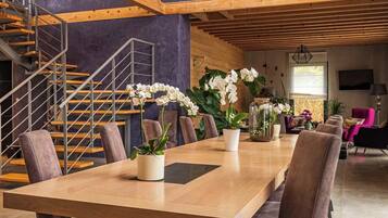 Uma sala de jantar moderna com mesa de madeira, cadeiras e plantas em vasos.