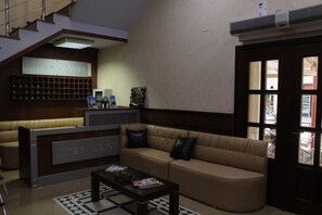 Um hall com balcão de recepção, um sofá, uma mesa de centro e um tapete estampado.