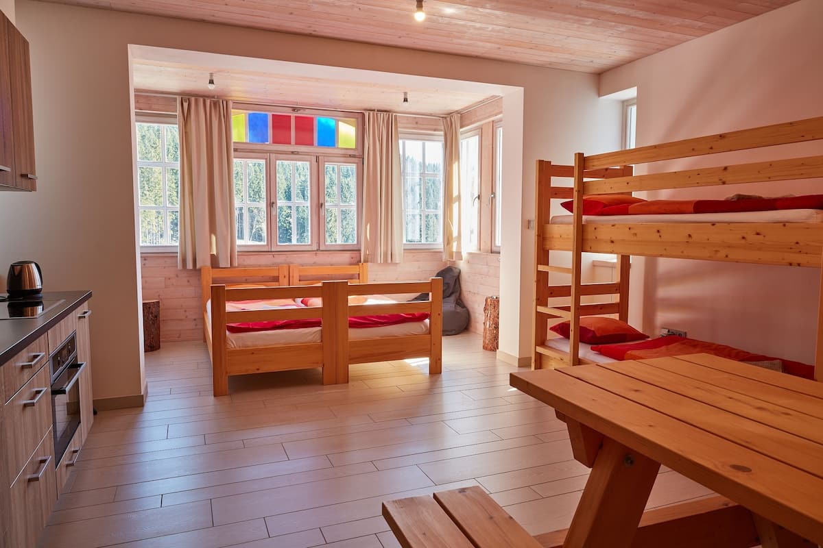 Um quarto acolhedor com beliches de madeira, uma mesa de madeira e uma janela com cortinas.