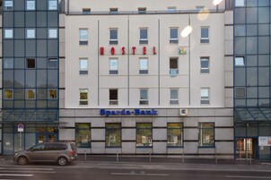 Um edifício de hostel com uma placa que diz "HOSTEL" e um banco chamado "Sparda-Bank" abaixo.