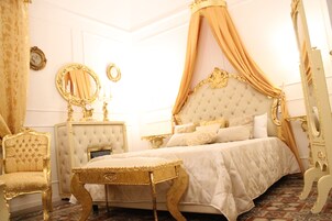 Um quarto luxuoso com uma cama grande, móveis dourados ornamentados e um dossel.