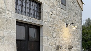 Um edifício de pedra com porta de madeira escura e janela com grades de metal.