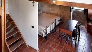 Interior rústico de madeira com cama no mezanino, uma mesa de jantar e escada.