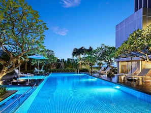 Uma piscina com espreguiçadeiras, um tobogã e um edifício moderno ao fundo.