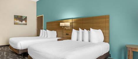 Quarto de hotel com duas camas, cabeceira de madeira, mesa de cabeceira com abajur e um quadro na parede.