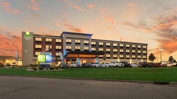 Um hotel Holiday Inn Express & Suites com estacionamento e área gramada na frente.