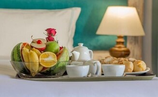 Uma bandeja de café da manhã com uma tigela de frutas, um bule, xícaras e doces.