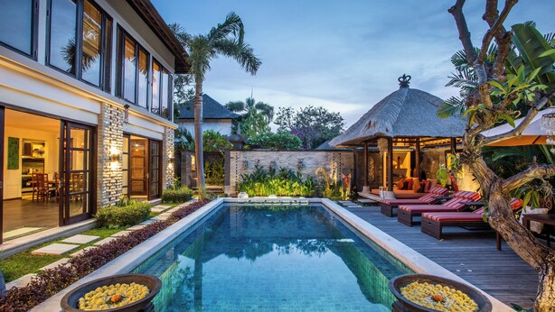 Um resort moderno com piscina, área de estar e estrutura com telhado de palha.