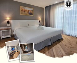 Quarto de hotel com cama grande, escrivaninha com cadeira, banheiro e vista para o exterior.